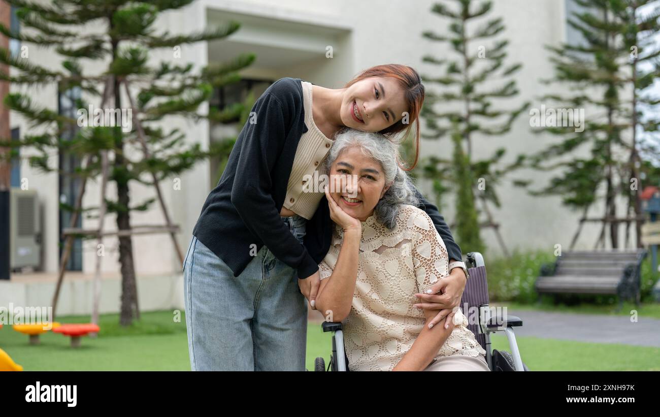 A lovely Asian granddaughter is hugging her grandma, who is in a ...