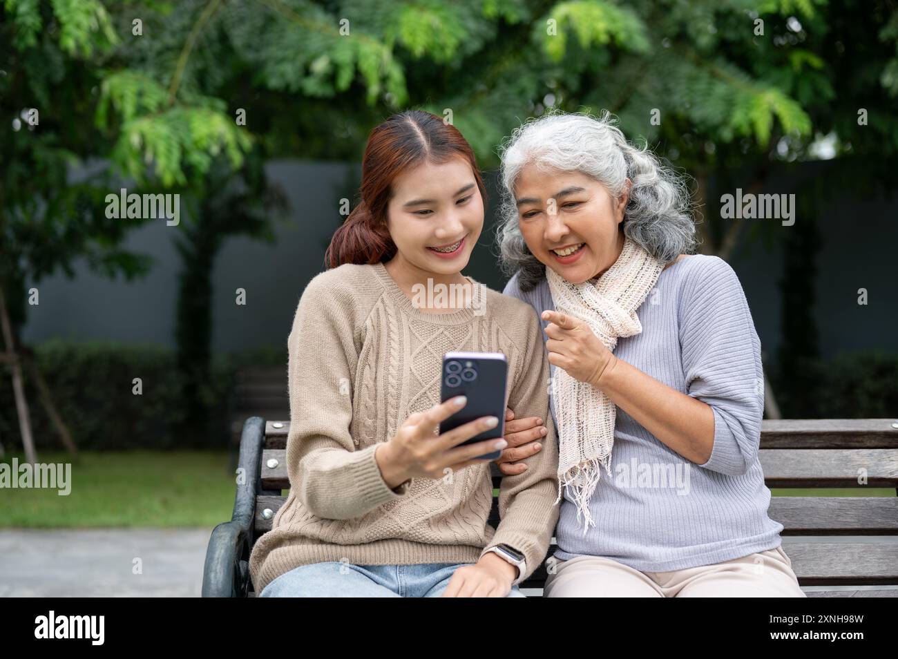 A caring, happy Asian granddaughter is showing a video on her ...
