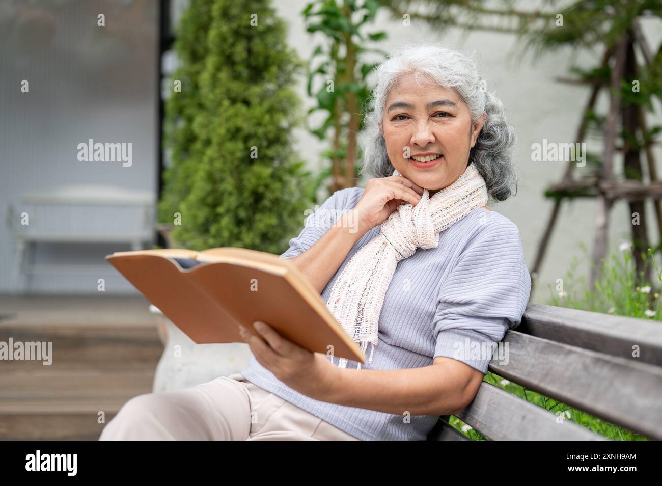 A happy retired Asian woman in casual clothes is smiling at the camera ...