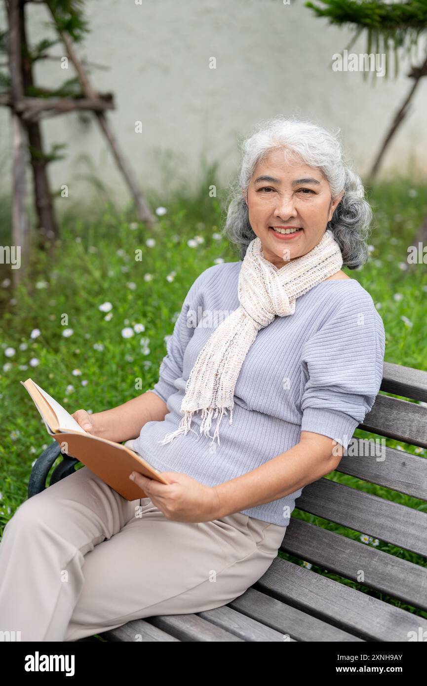 A happy retired Asian woman in casual clothes is smiling at the camera ...