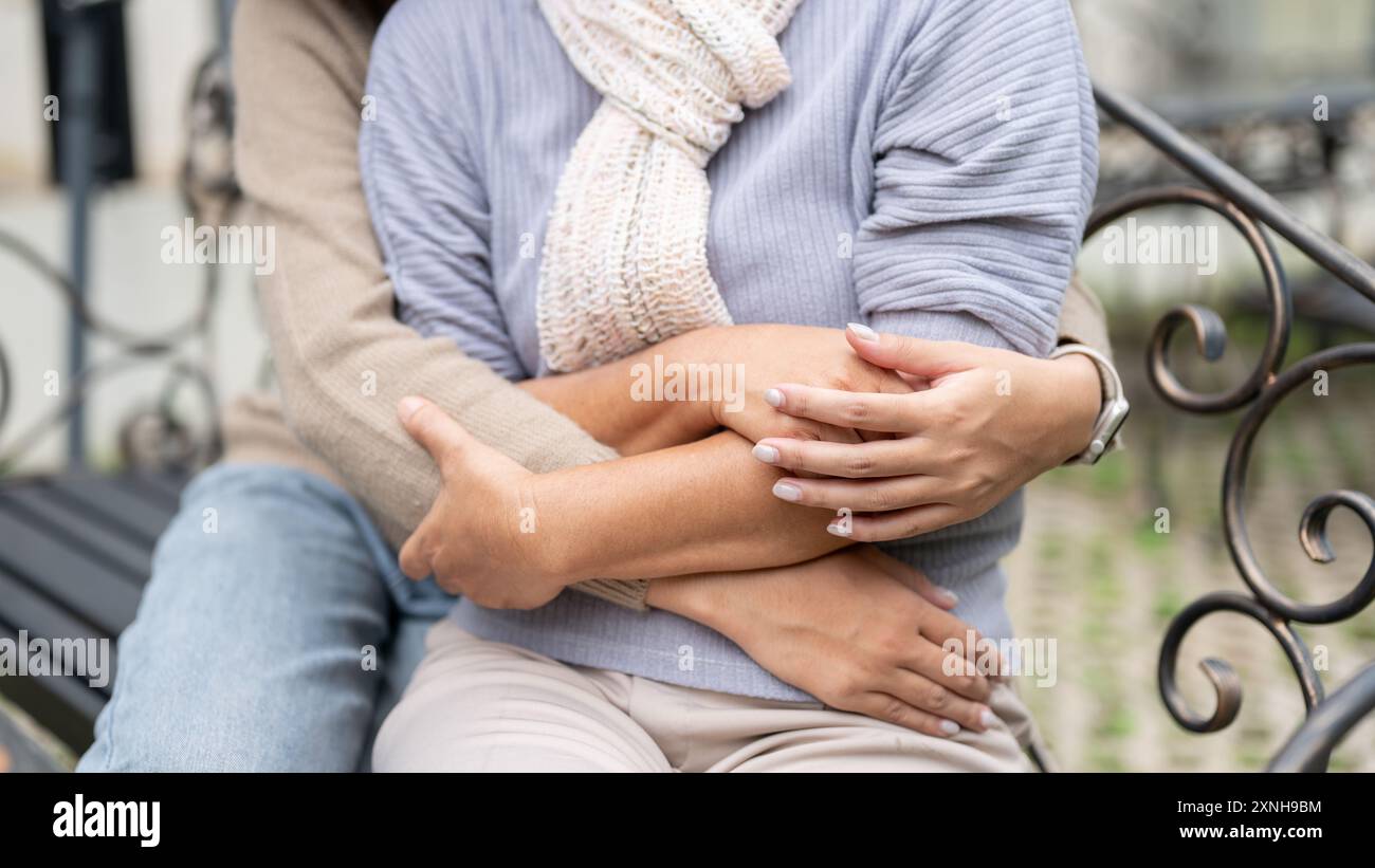 A cropped close-up image of a daughter holding hand and hugging her mom ...