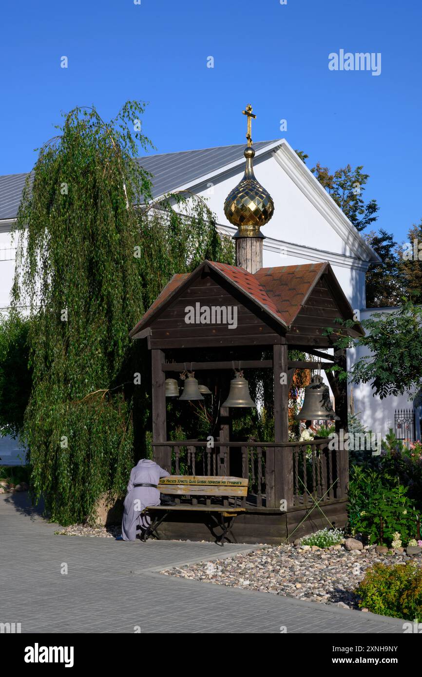 A thoughtful pilgrim on a bench near a gazebo with bells, dome and ...