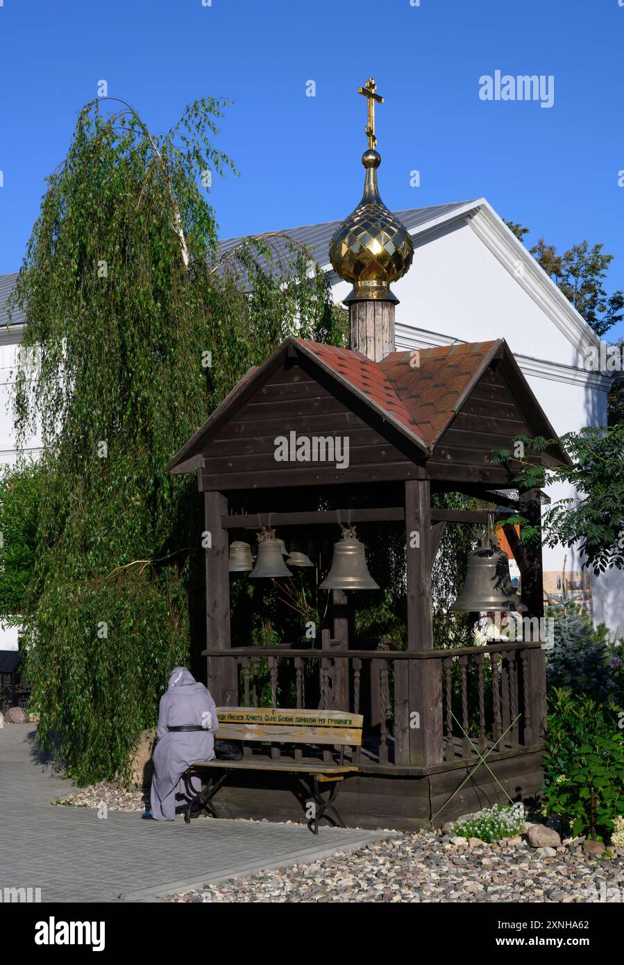 A thoughtful pilgrim on a bench near a gazebo with bells, dome and ...