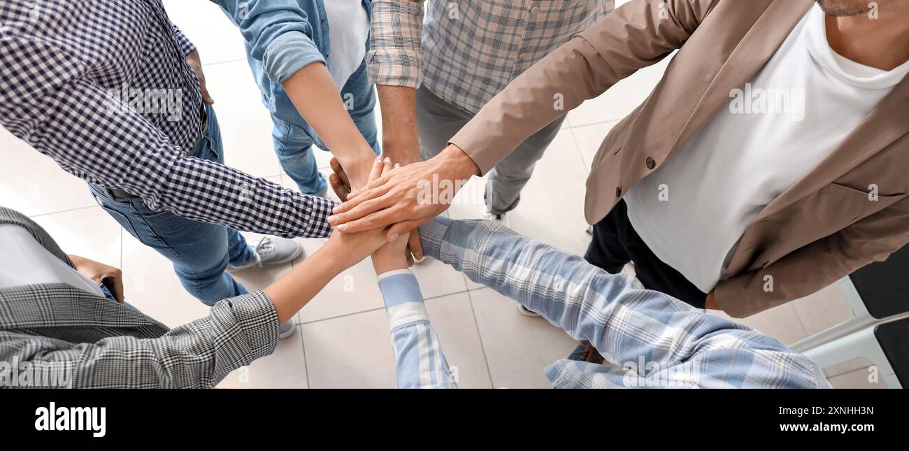 Group of people putting hands together indoors, top view. Unity concept ...