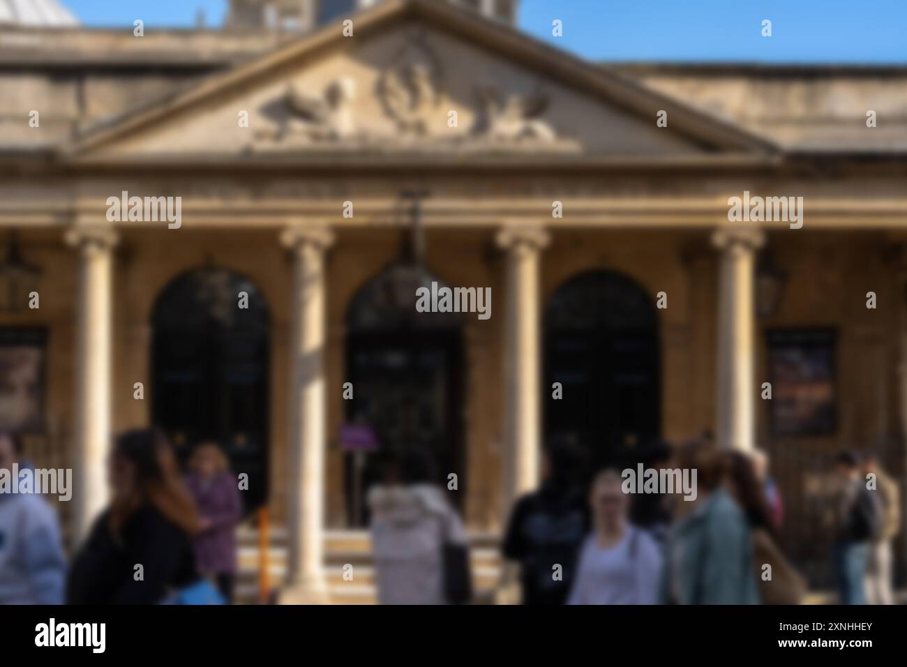 An out-of-focus image shows a group of people walking past a large ...
