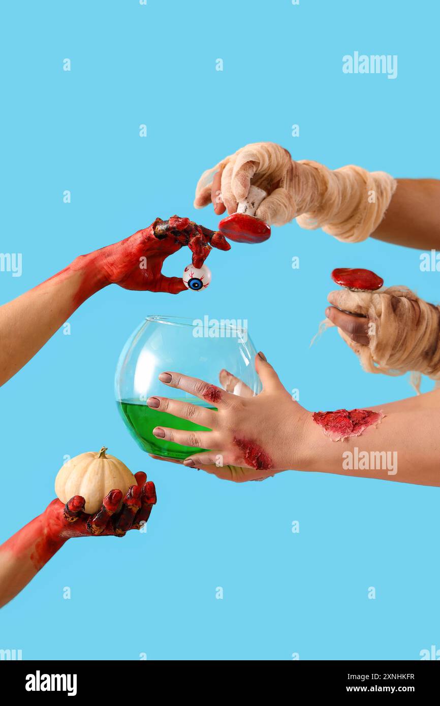 Zombie hands holding glass bowl with poison and ingredients on blue ...