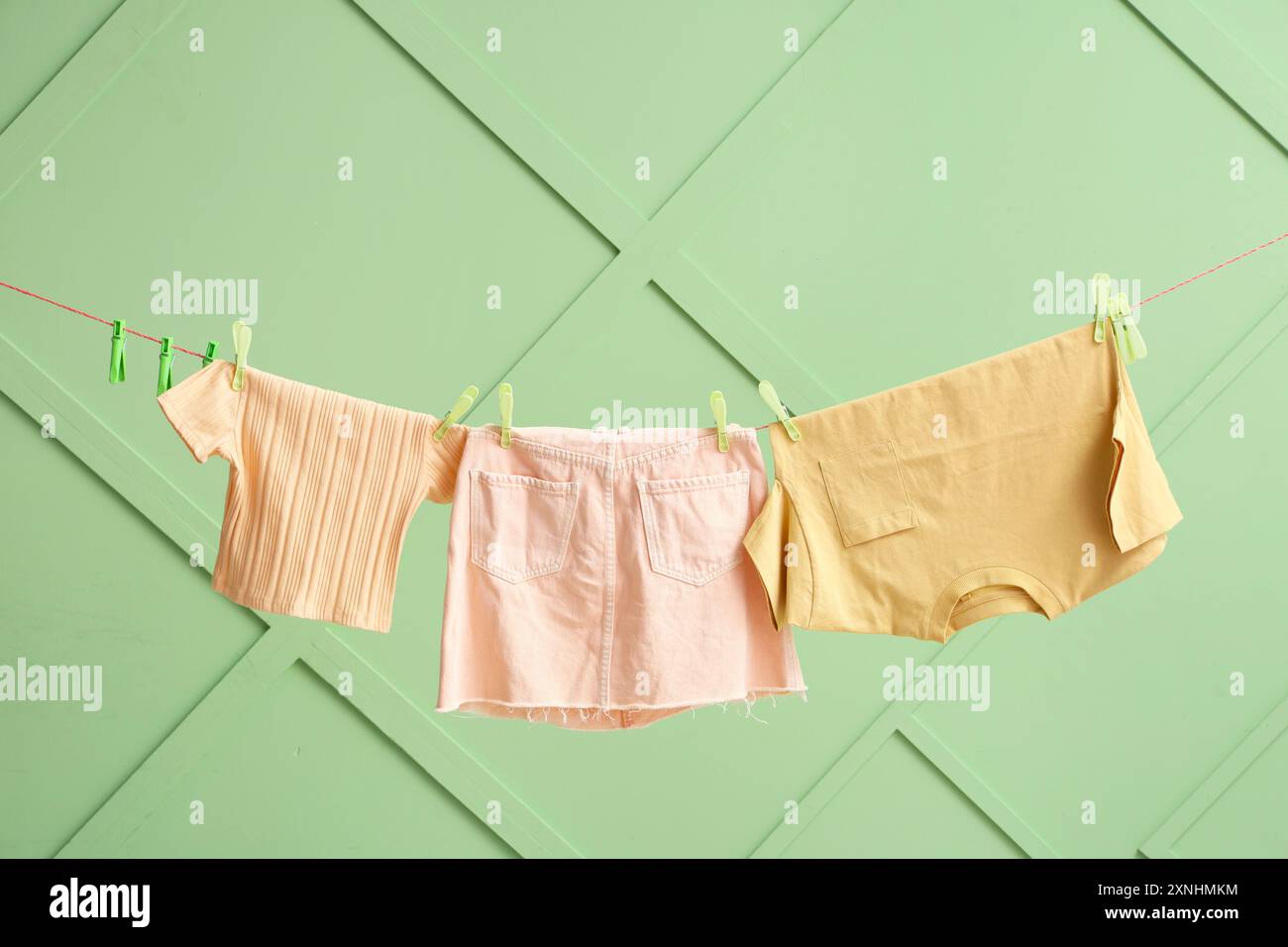 Clean clothes hanging on rope against color wall Stock Photo - Alamy