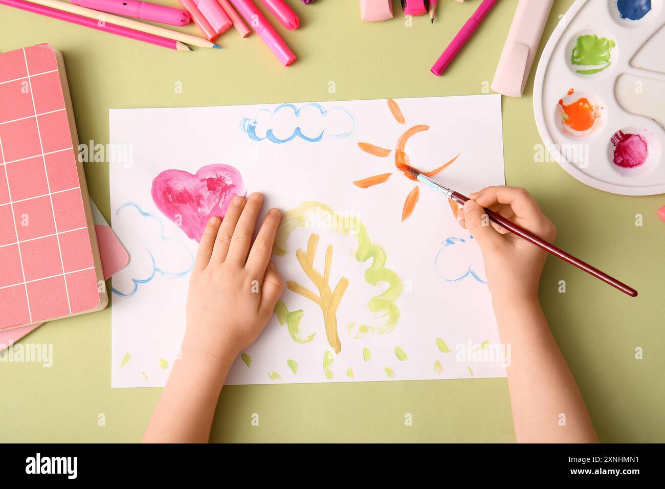 Child's hand drawing sun with brush, watercolor paints and different ...