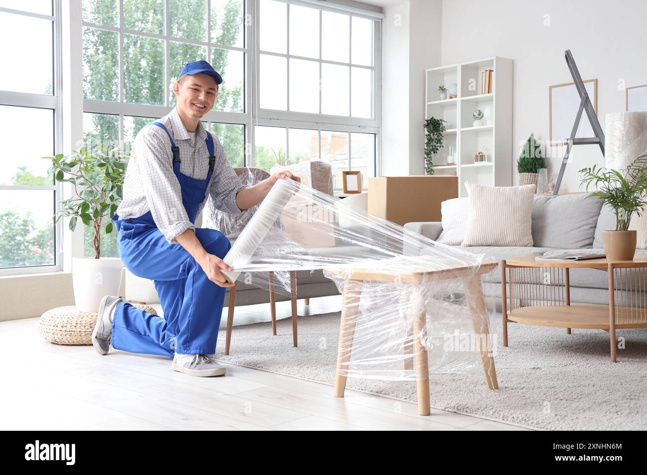 Male worker wrapping table with stretch film in room Stock Photo - Alamy