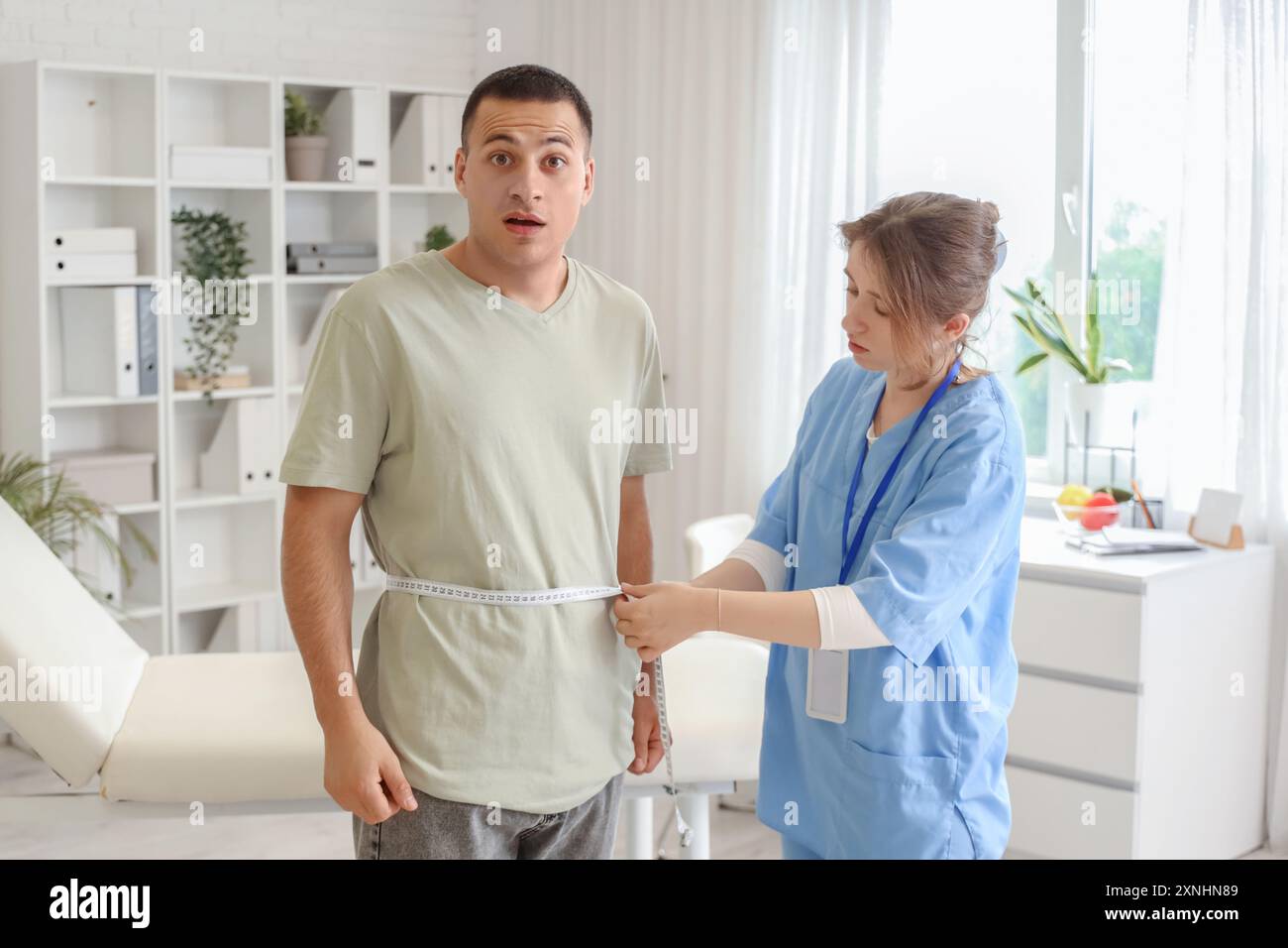 Female doctor measuring man's waist in clinic Stock Photo - Alamy