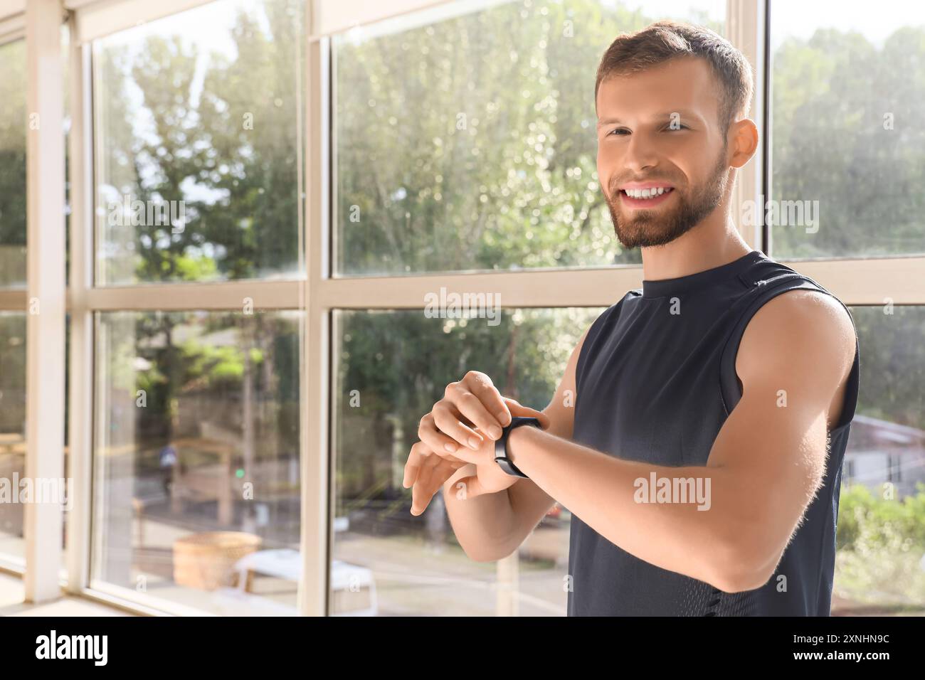 Sporty young man with smartwatch checking his pulse near window Stock ...
