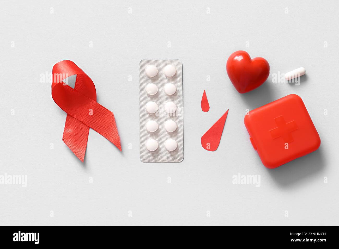 Red ribbon with paper blood drops, pills and heart on grey background ...