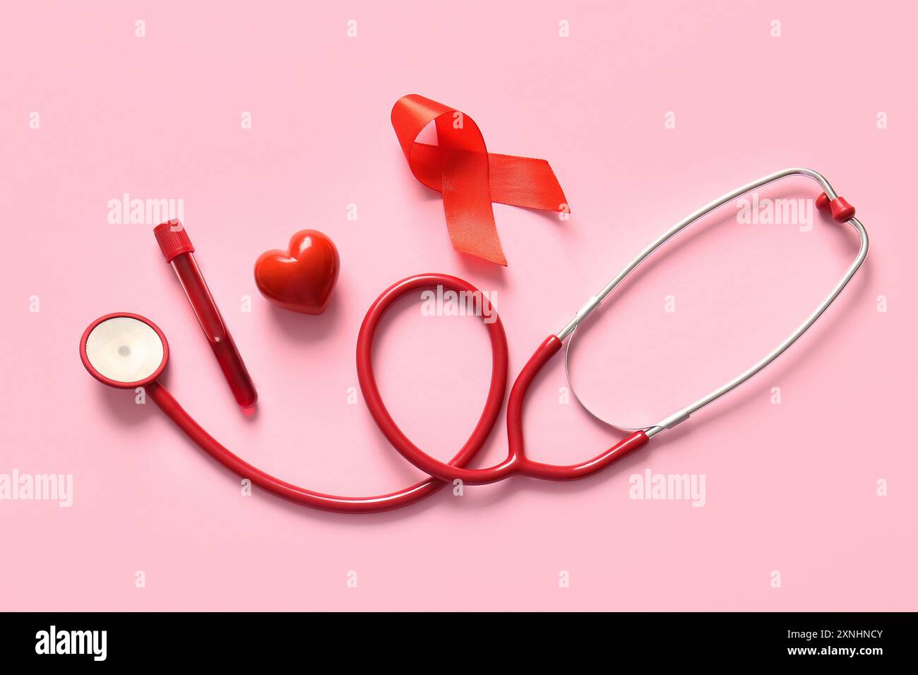 Red ribbon with stethoscope, blood sample and heart on pink background ...