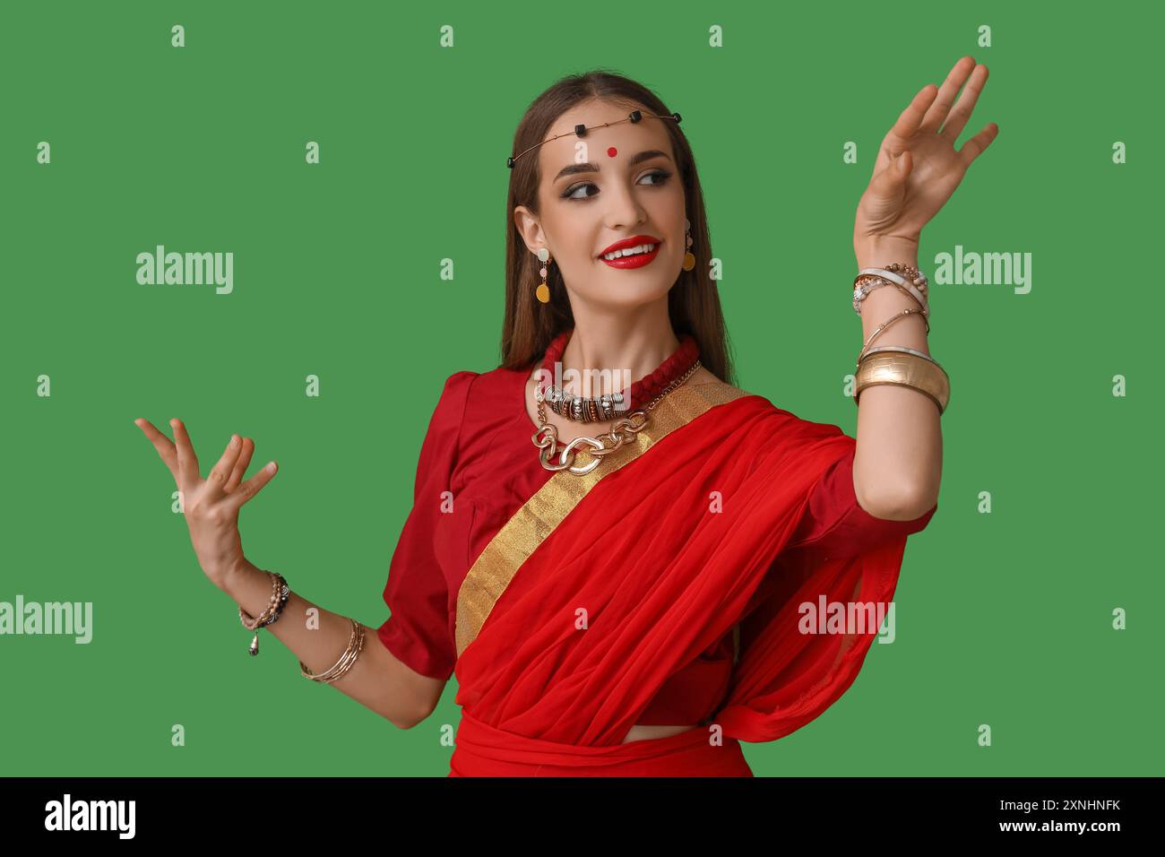 Beautiful young happy Indian woman in sari dancing on green background ...