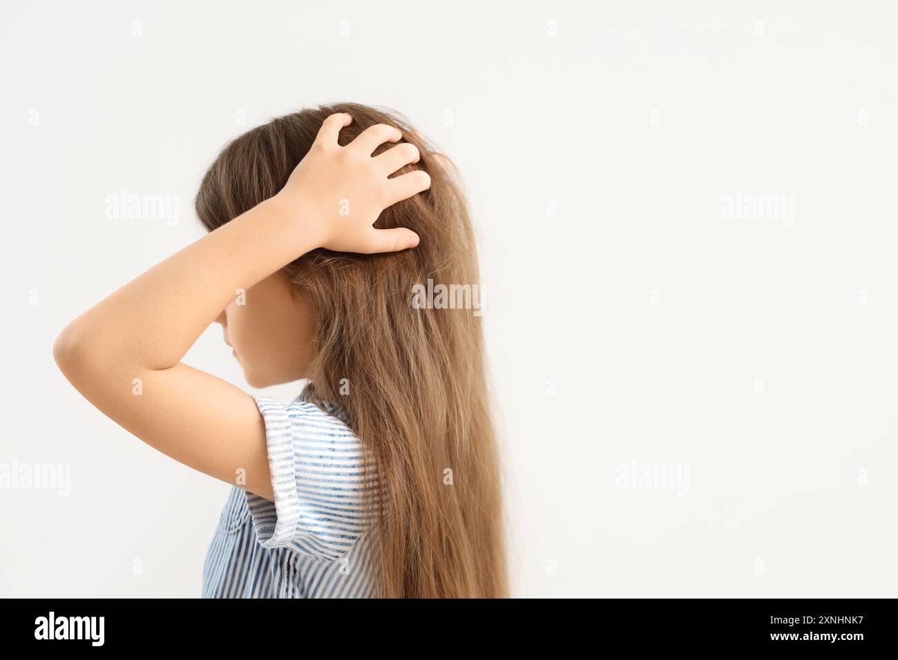 Little girl with pediculosis scratching her head on light background ...