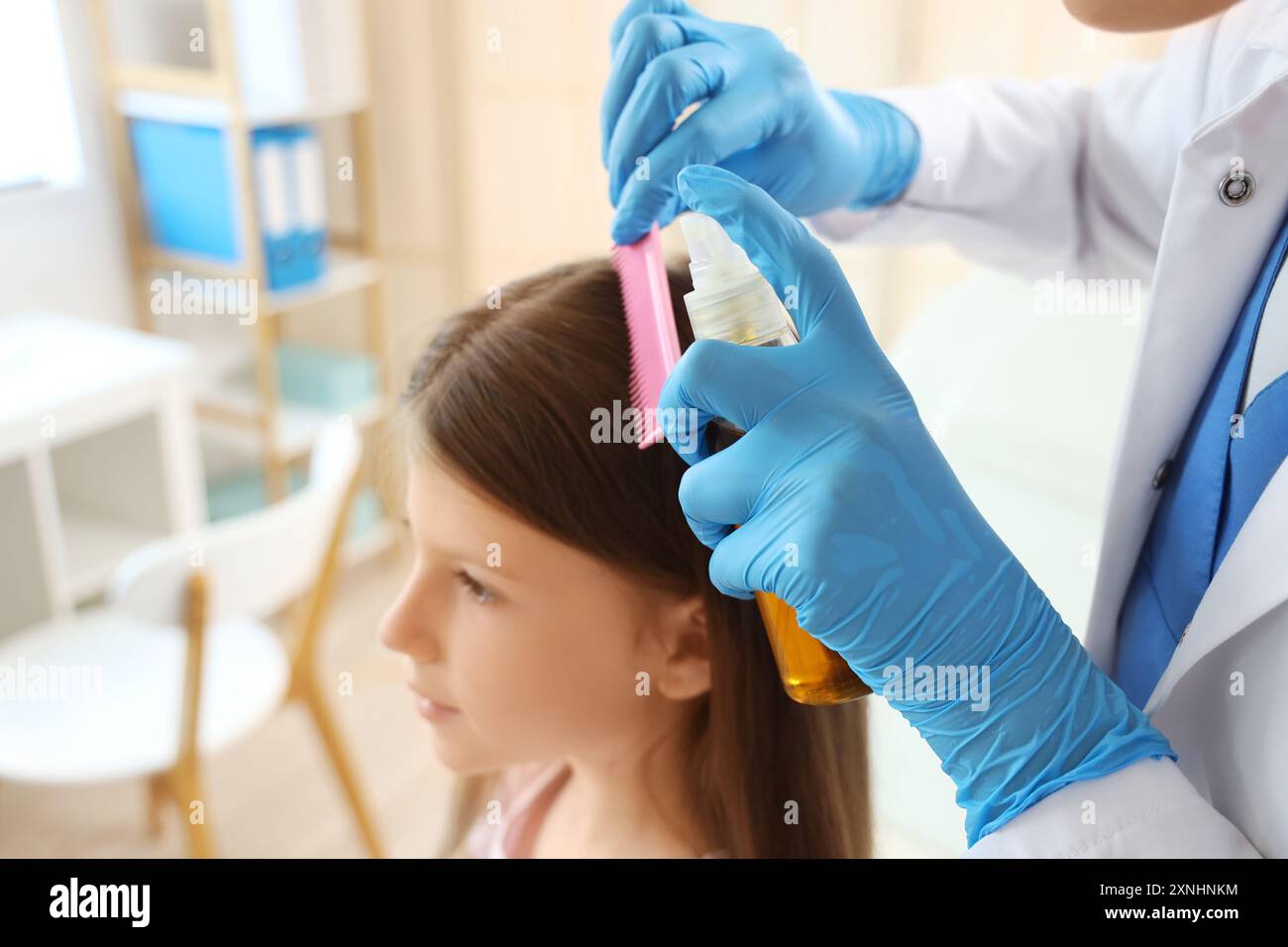 Female doctor spraying little girl's hair with pediculosis in clinic ...