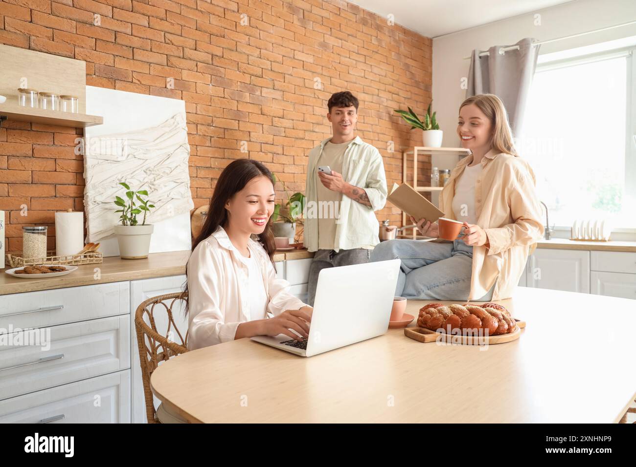 Young man with two women spending time together in kitchen. Polyamory ...