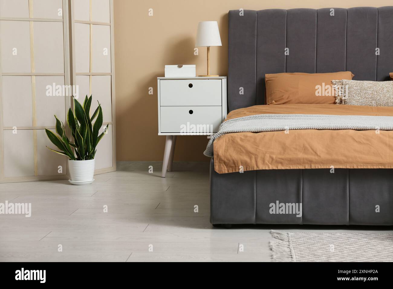 Interior of stylish bedroom with big bed, table and folding screen ...