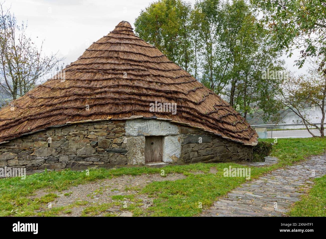Rustic thatched-roof cottage with circular shape in rural landscape ...