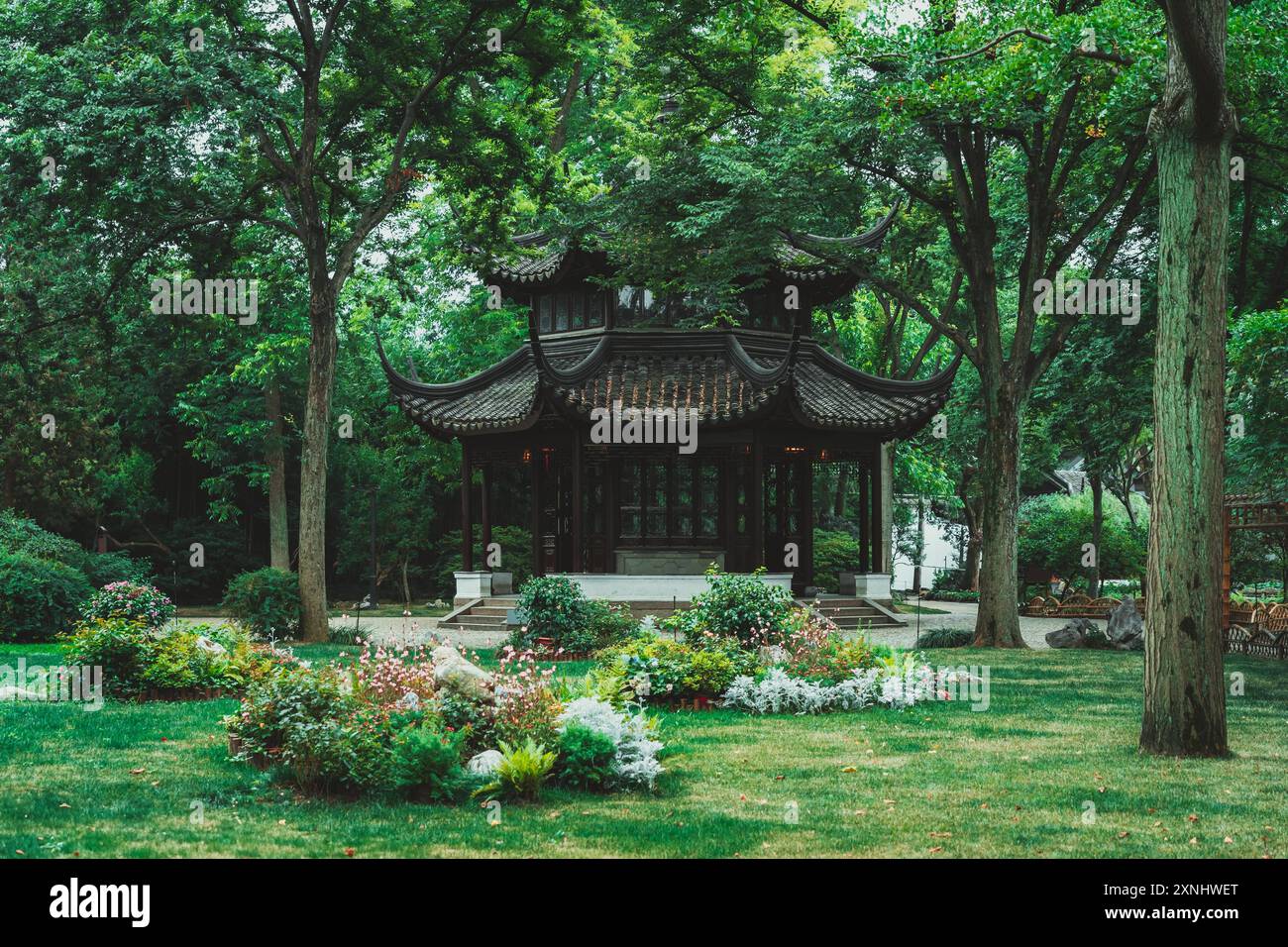A traditional Chinese garden pavilion surrounded by lush greenery in ...