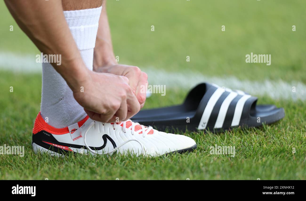 Footballer tying up his Nike football boots and Adidas Sliders Stock ...