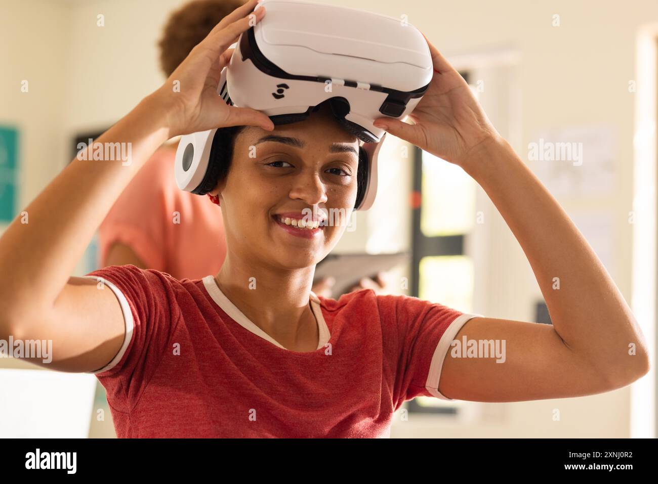 Using VR headset, smiling teenager in high school classroom, enjoying ...