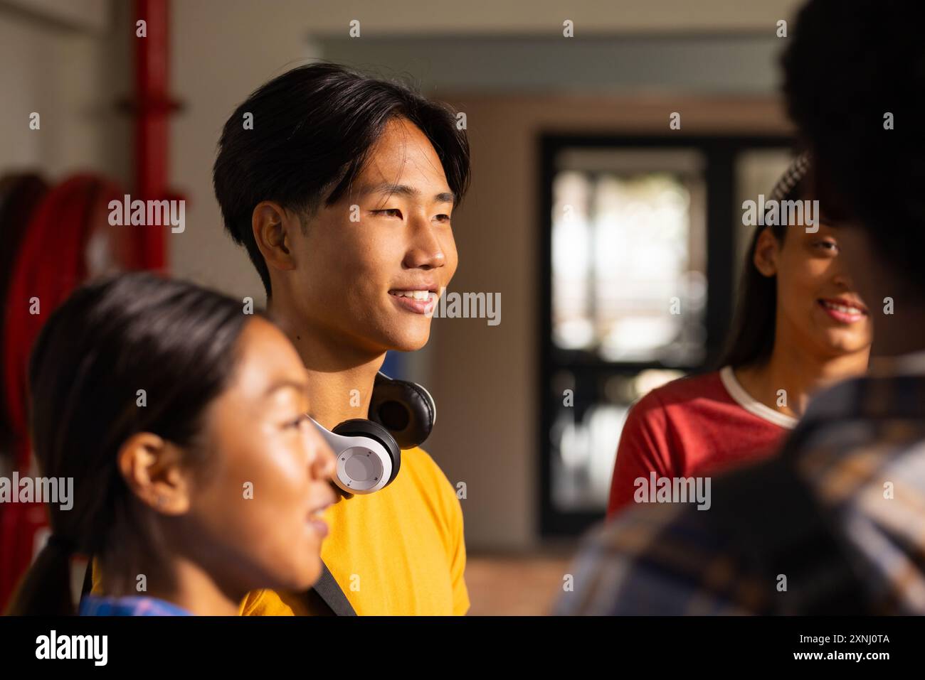 Teenager with headphones smiling and talking with friends at high ...
