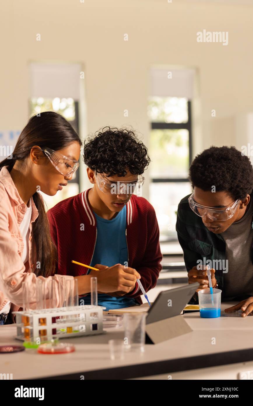 Conducting science experiment, teenagers using tablet and lab equipment ...