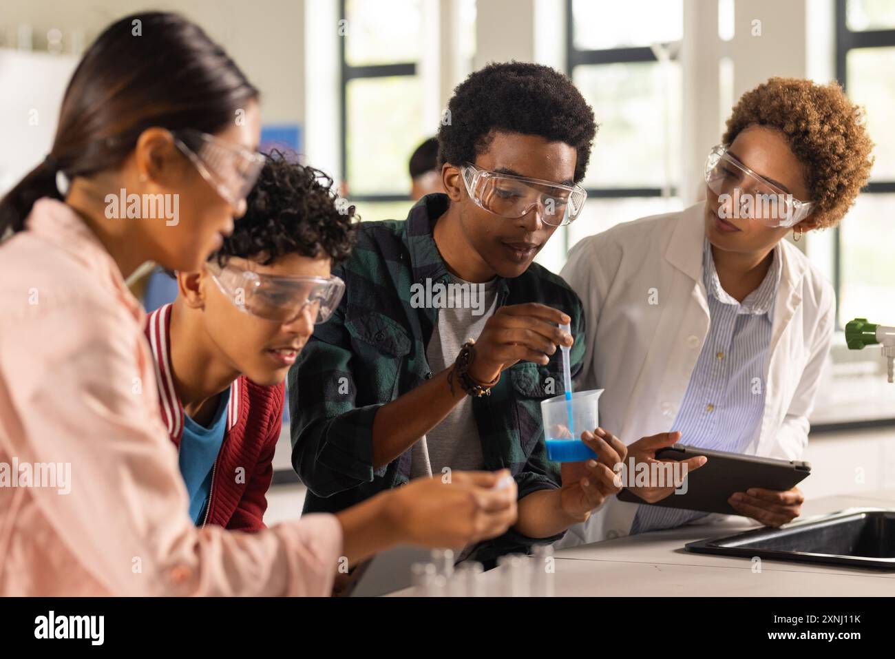 Conducting science experiment in high school, students with teacher supervising in classroom ...