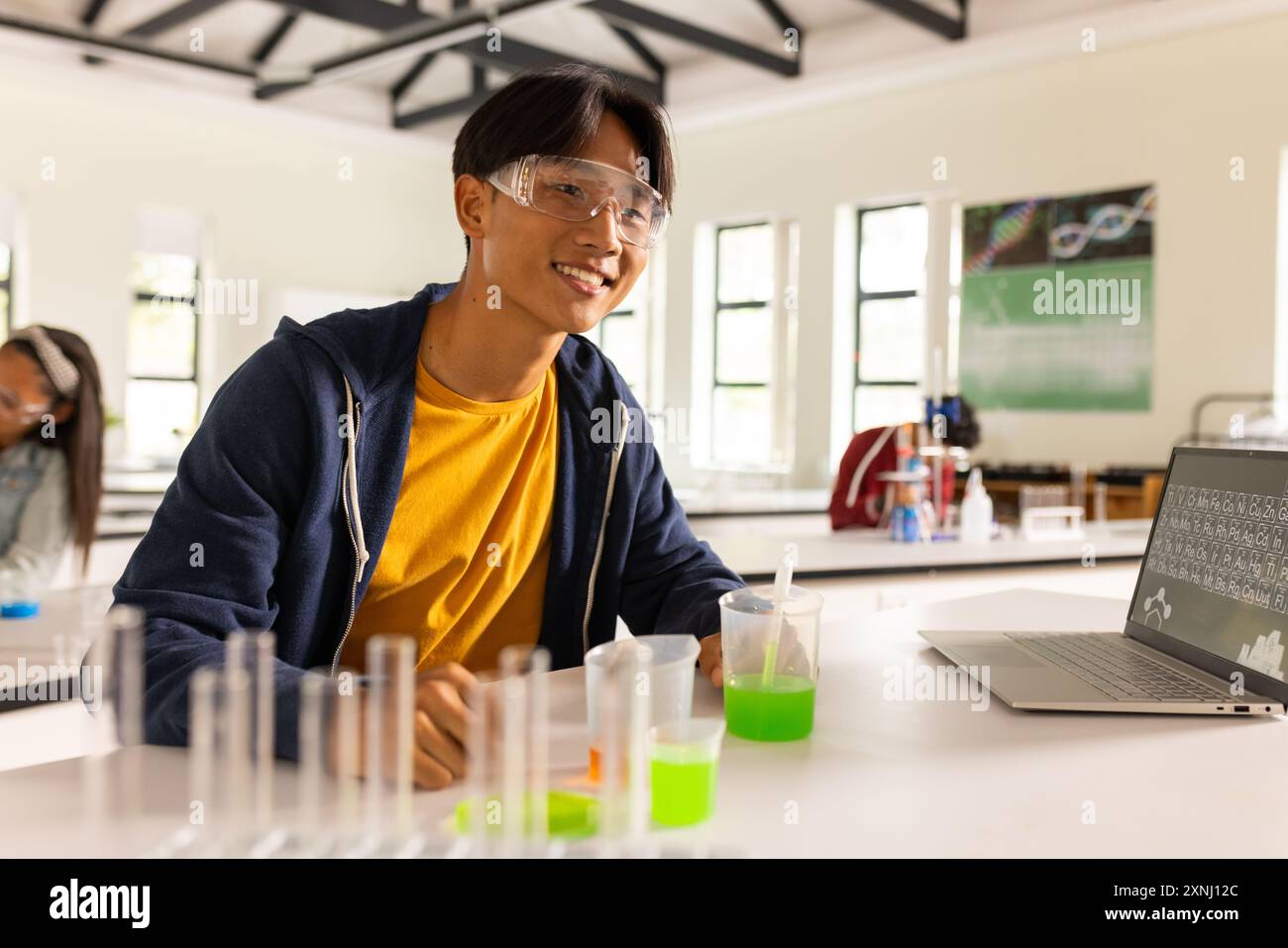 Conducting science experiment with laptop and test tubes, teenager in ...