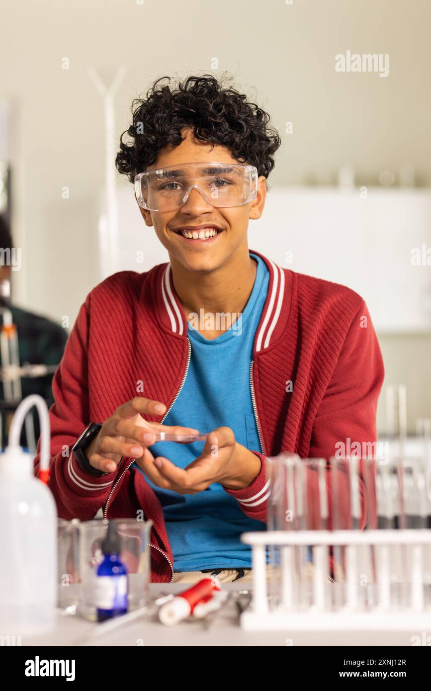 Wearing safety goggles, teenager conducting science experiment in high ...