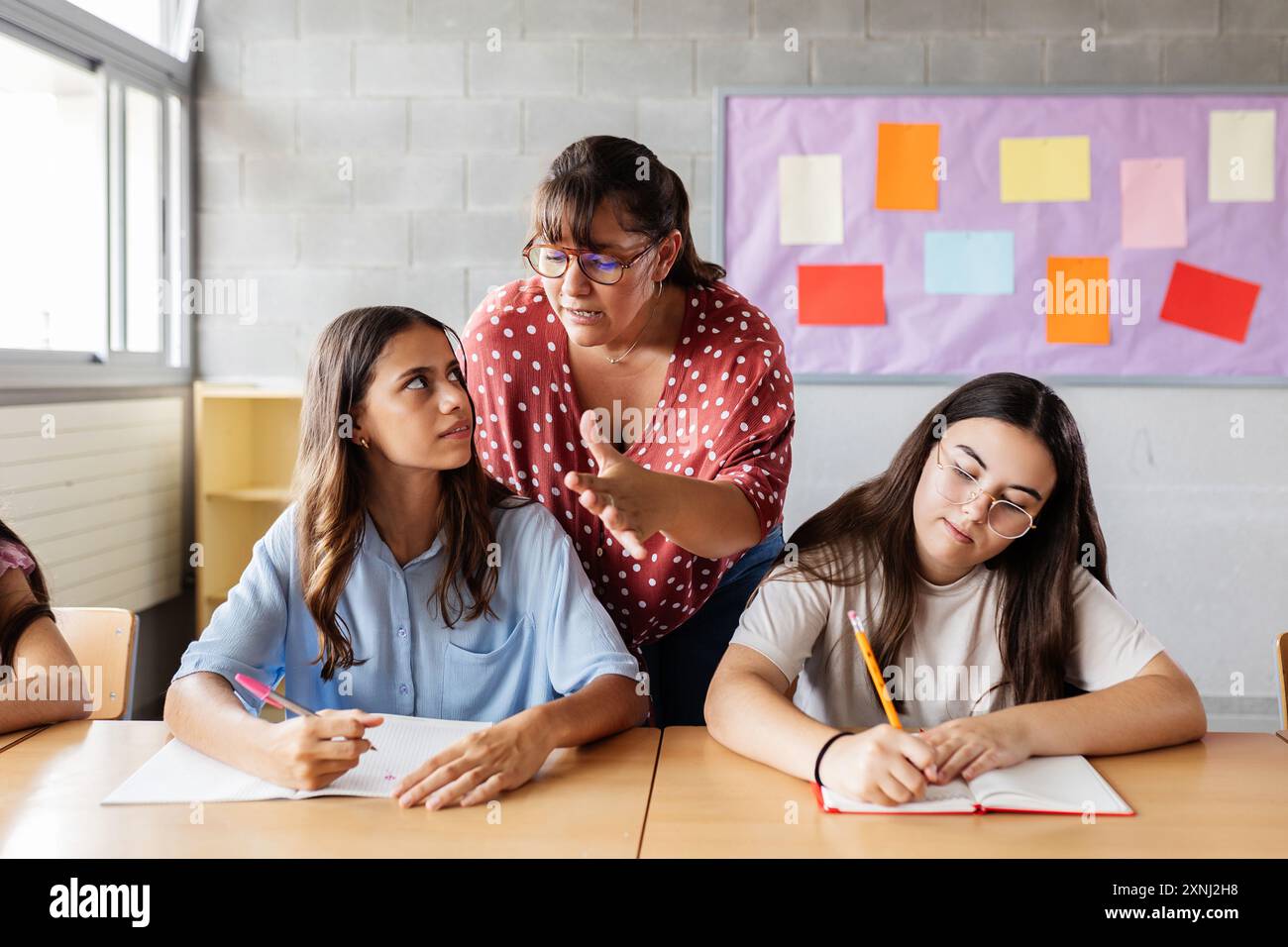 Female teacher assisting elementary student during lesson at school ...