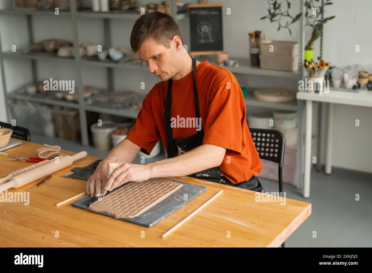 A potter cuts a piece of rolled clay with patterns Stock Photo - Alamy
