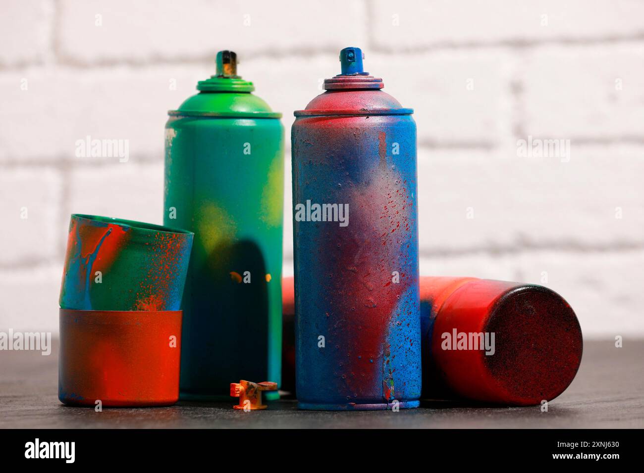 Many spray paint cans on gray surface against white brick wall Stock ...