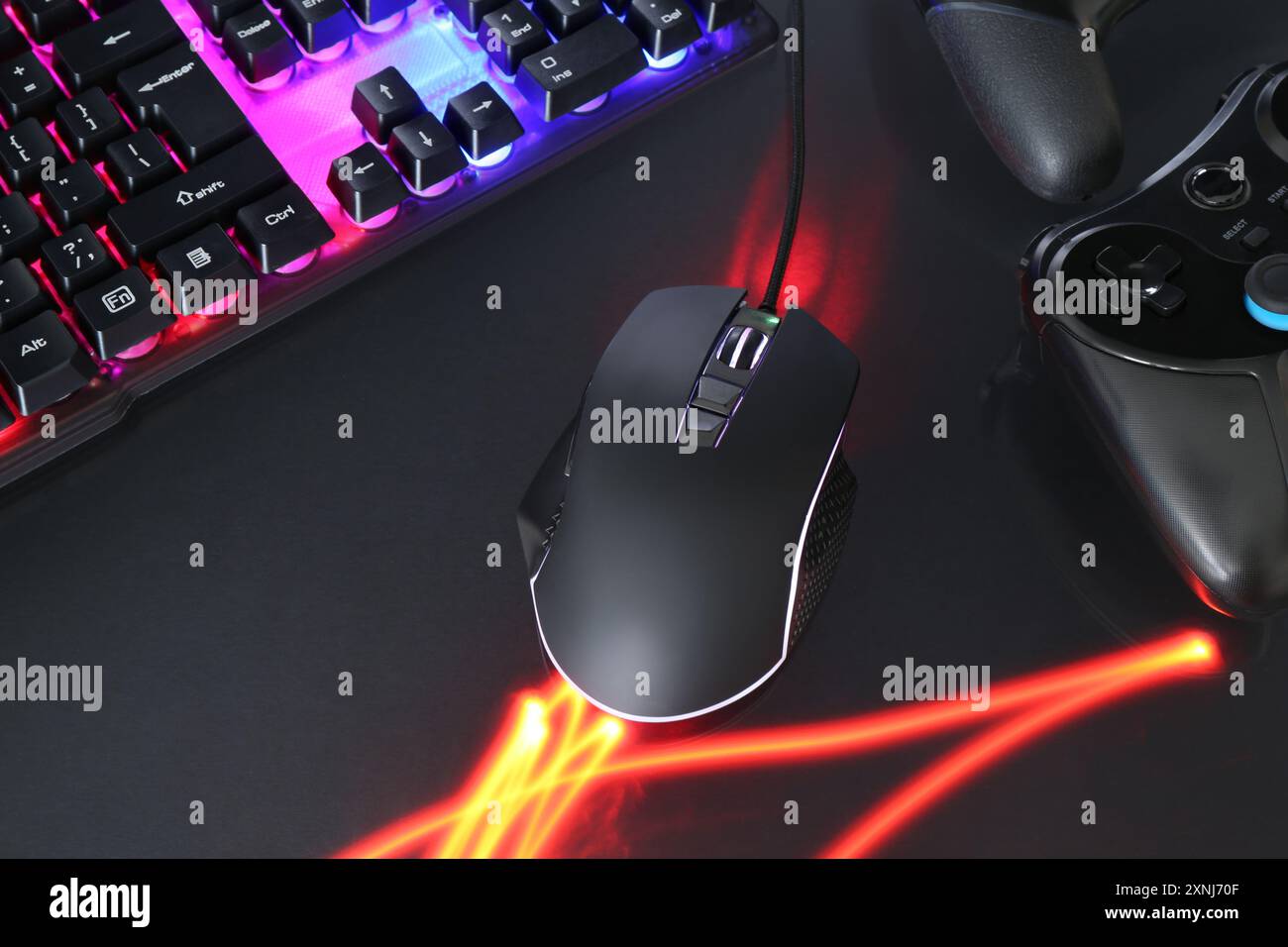 Computer mouse, RGB keyboard and game controllers in neon lights on ...