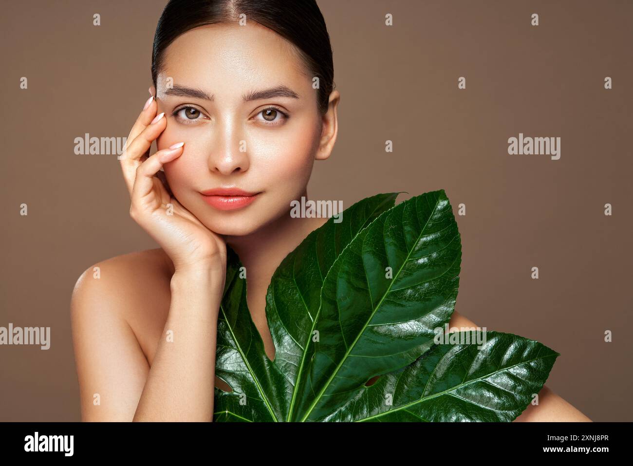 Close up woman face with green exotic leaf. Skin care beauty treatments ...