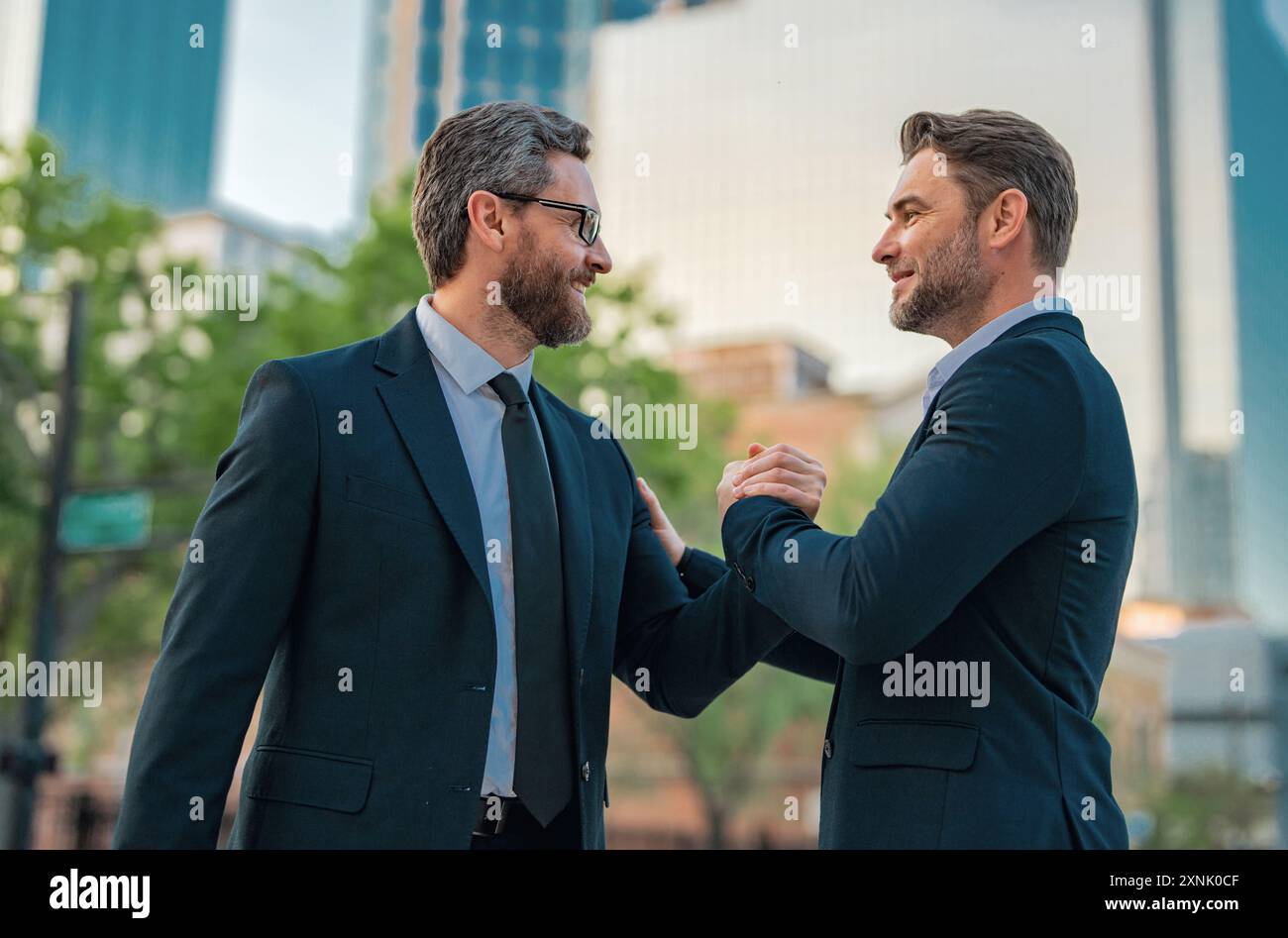 Two businessmen shaking hands on city street. Business men in suit ...