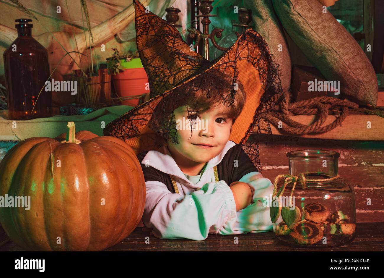 Surprised boy in Halloween costume holding orange pumpkin. Funny face ...