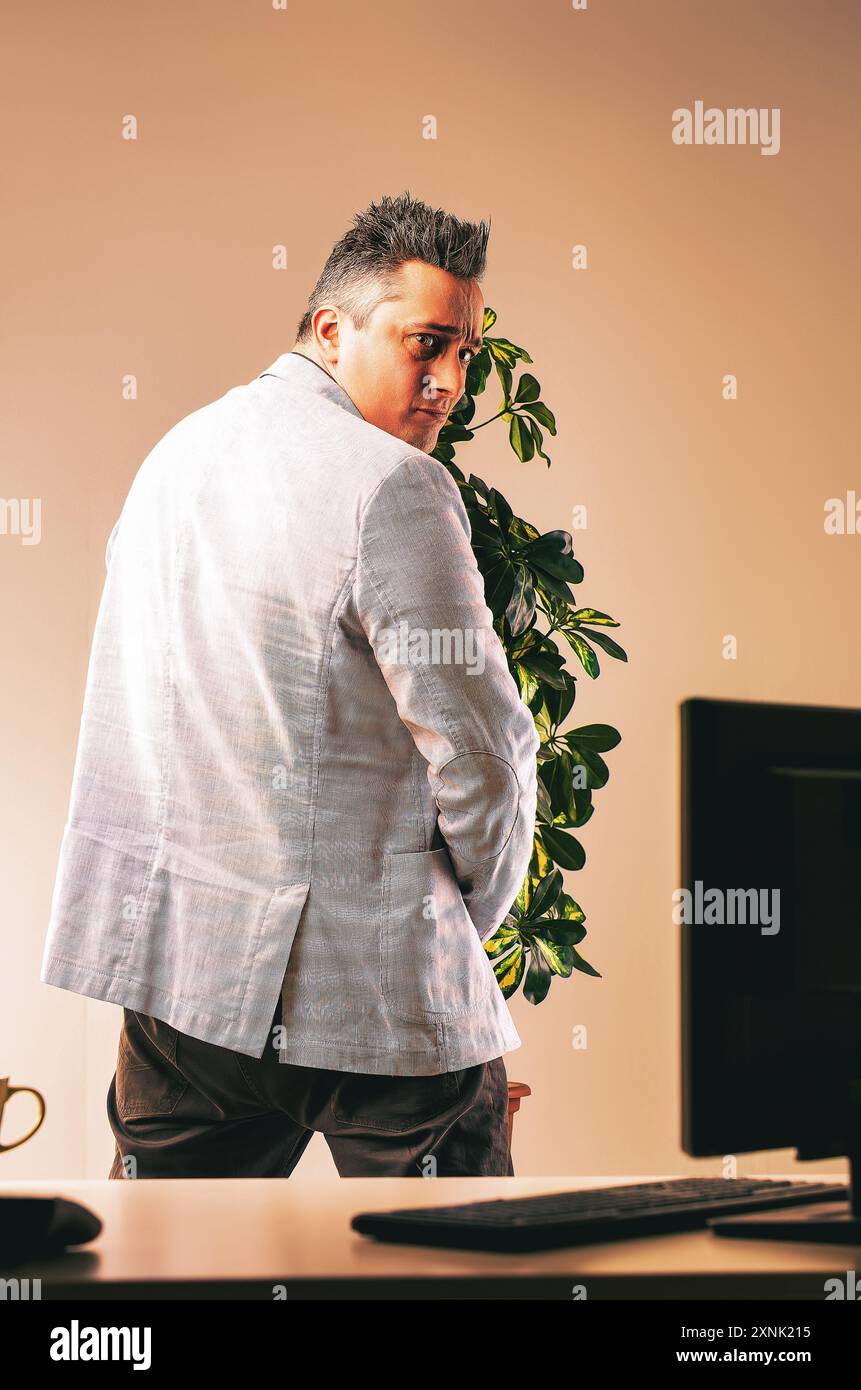 Manager hides behind a plant, peeking over his shoulder with a sneaky ...