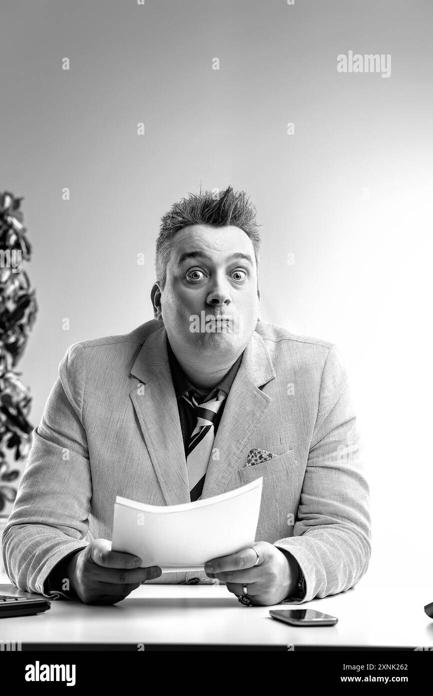 Shocked businessman at desk holding document, reacting to unexpected ...