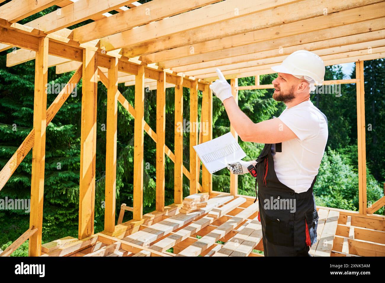 Carpenter constructing a wooden two-story frame house near the forest ...