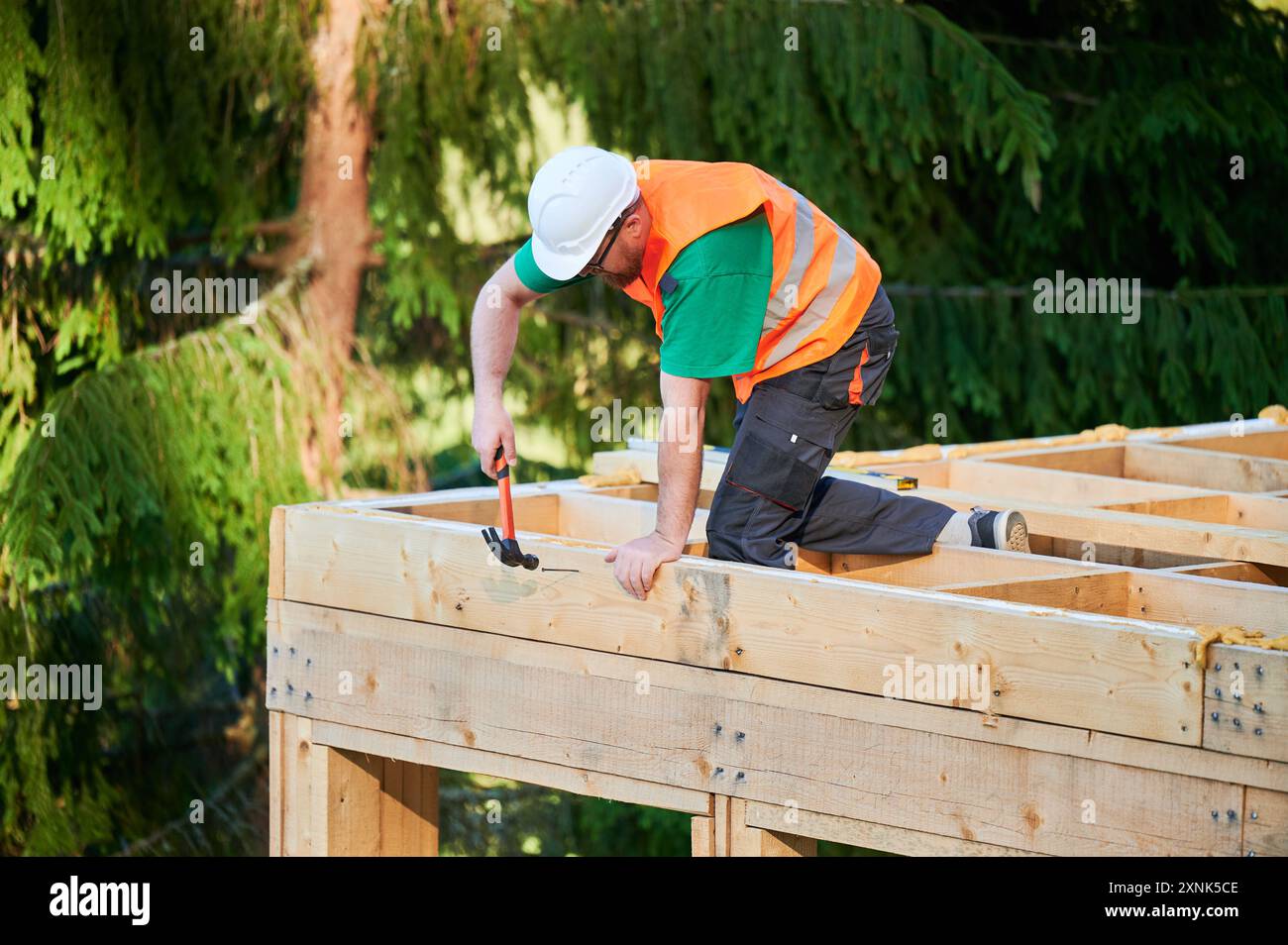 Carpenter constructing two-story wooden frame house near the forest ...
