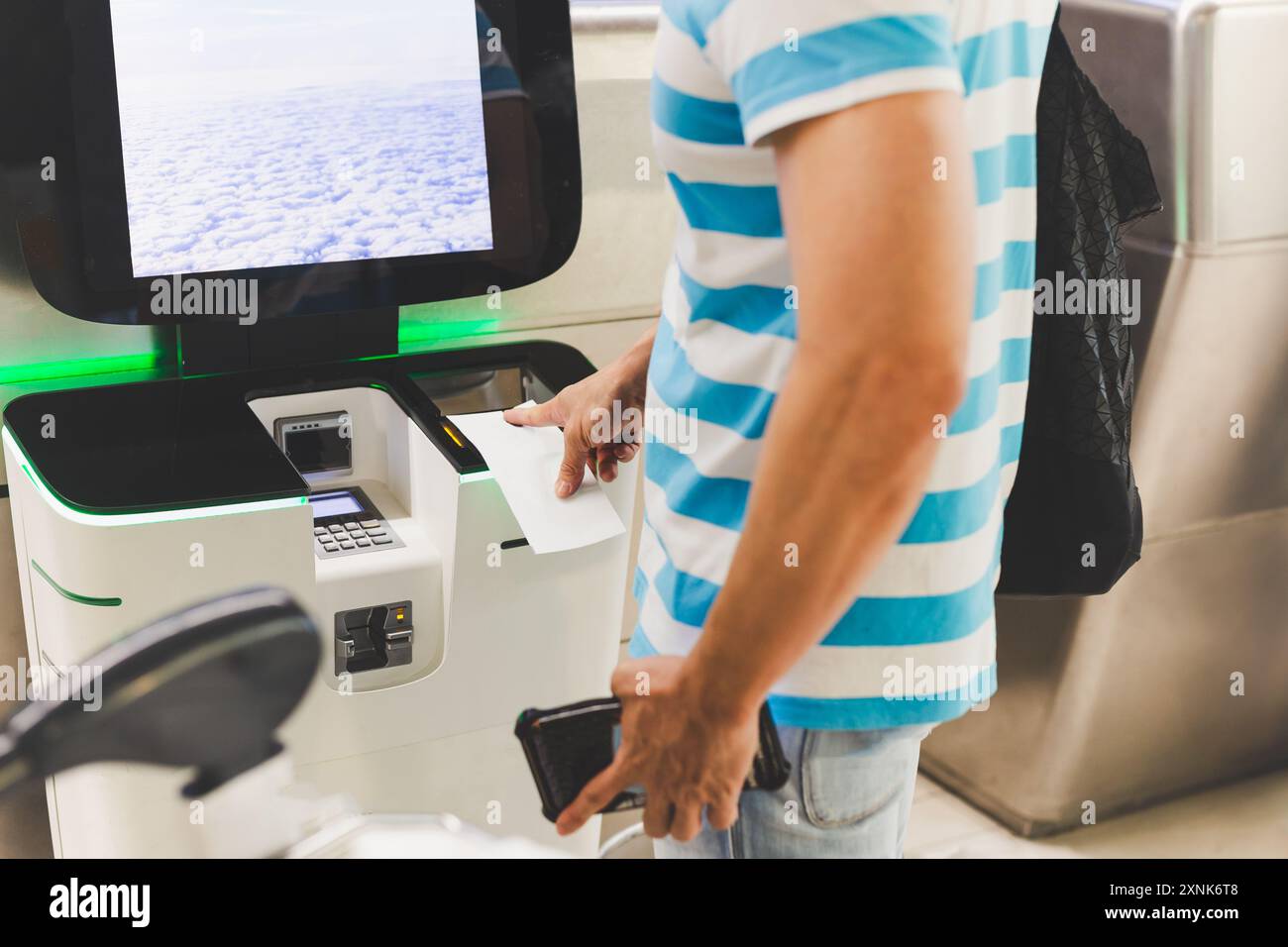 Male passenger doing self check in scanning boarding pass at airport ...