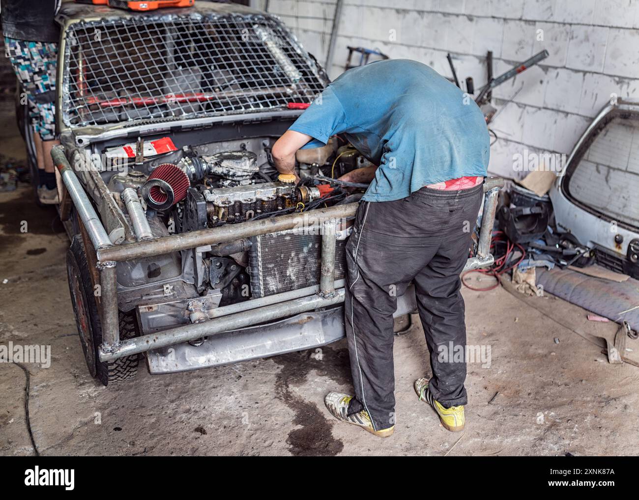 Teen putting final touches on a stock car in a workshop, part of a ...