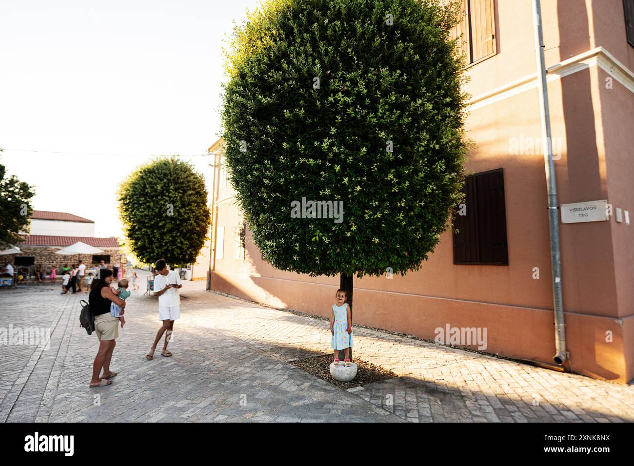 Family having a cheerful time in a sunny village square with children ...