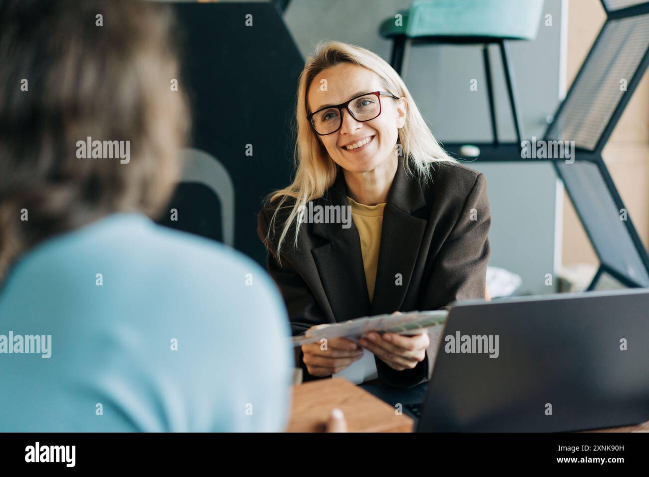 A smiling female consultant advises a client on the choice of color for ...