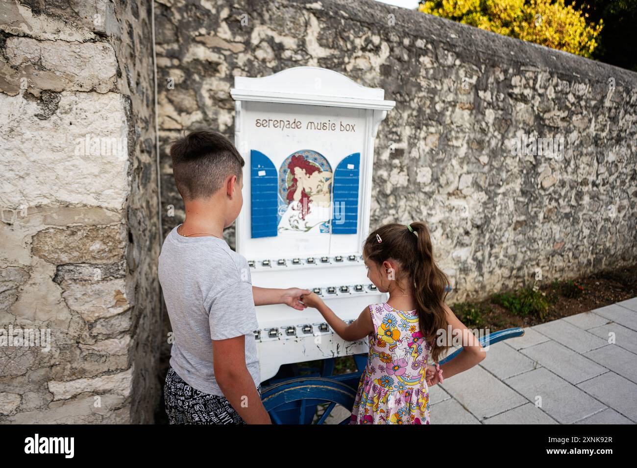 Two kids enjoying a melodious moment with a serenade music box outdoors ...