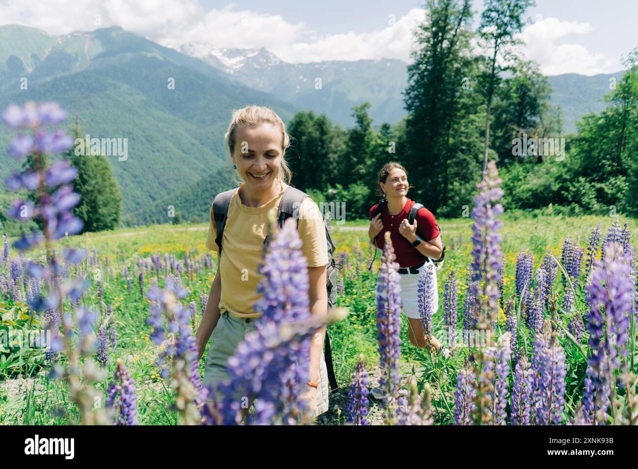 Two women hikers with backpacks walk along a mountain path Stock Photo ...