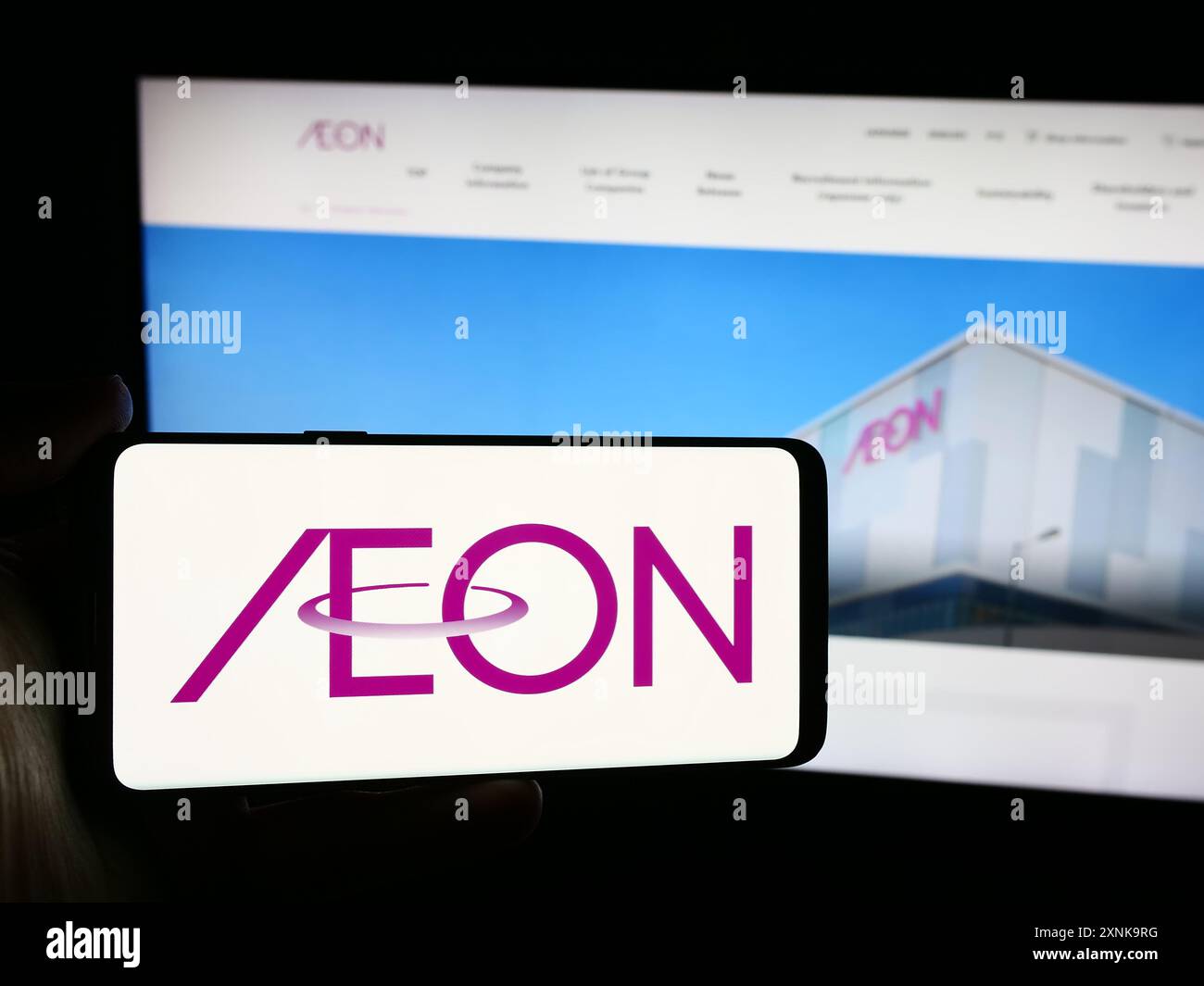 Person holding mobile phone with logo of Japanese retail holding ...