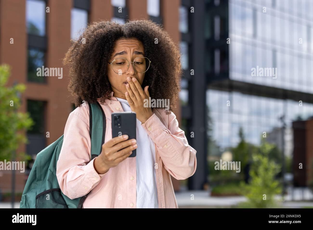 African american woman student looking at smartphone with shocked ...